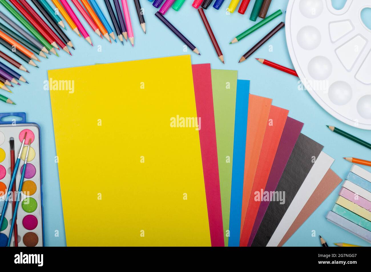 Art school supplies for painting and a set of colored paper on a blue ...