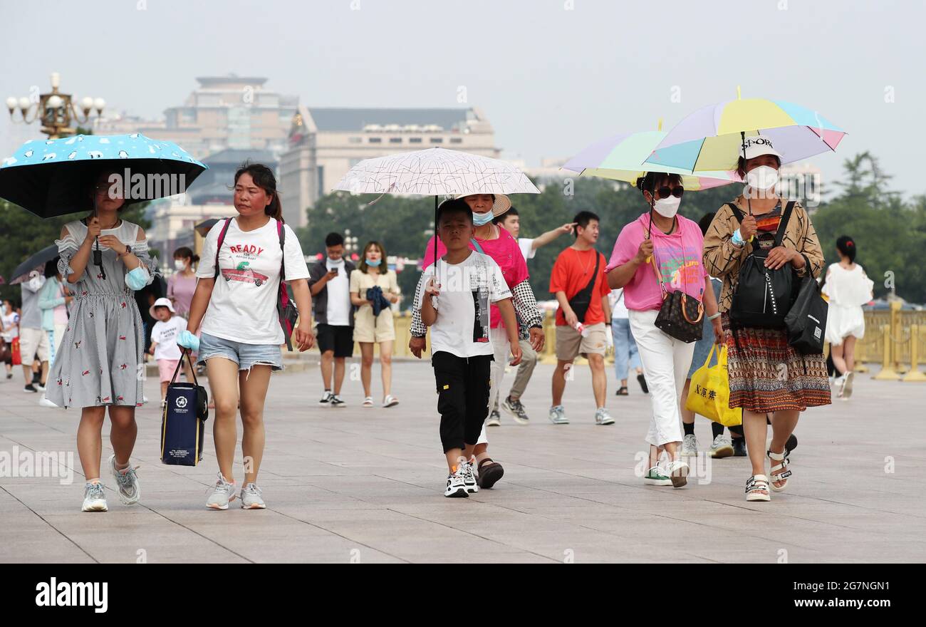 People walk under the sun with umbrellas and face masks in Beijing ...