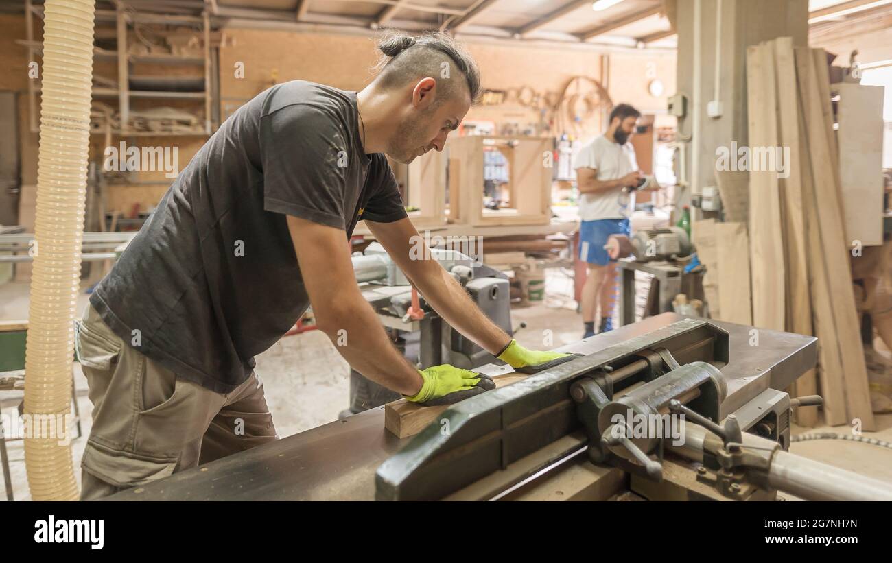 Carpenter processes wood in a furniture workshop. Woodworking and ...