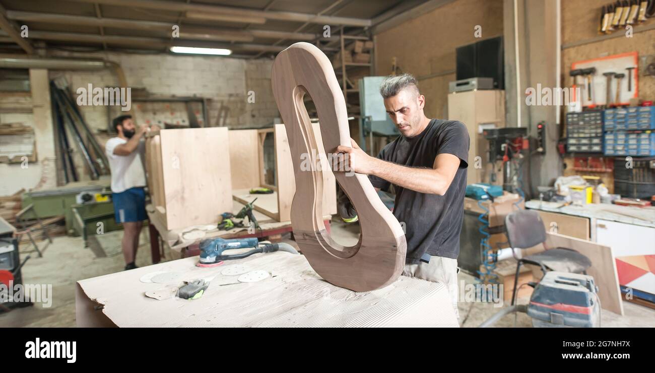 Craftsman is using an electric sander, to smoothen the wood texture ...