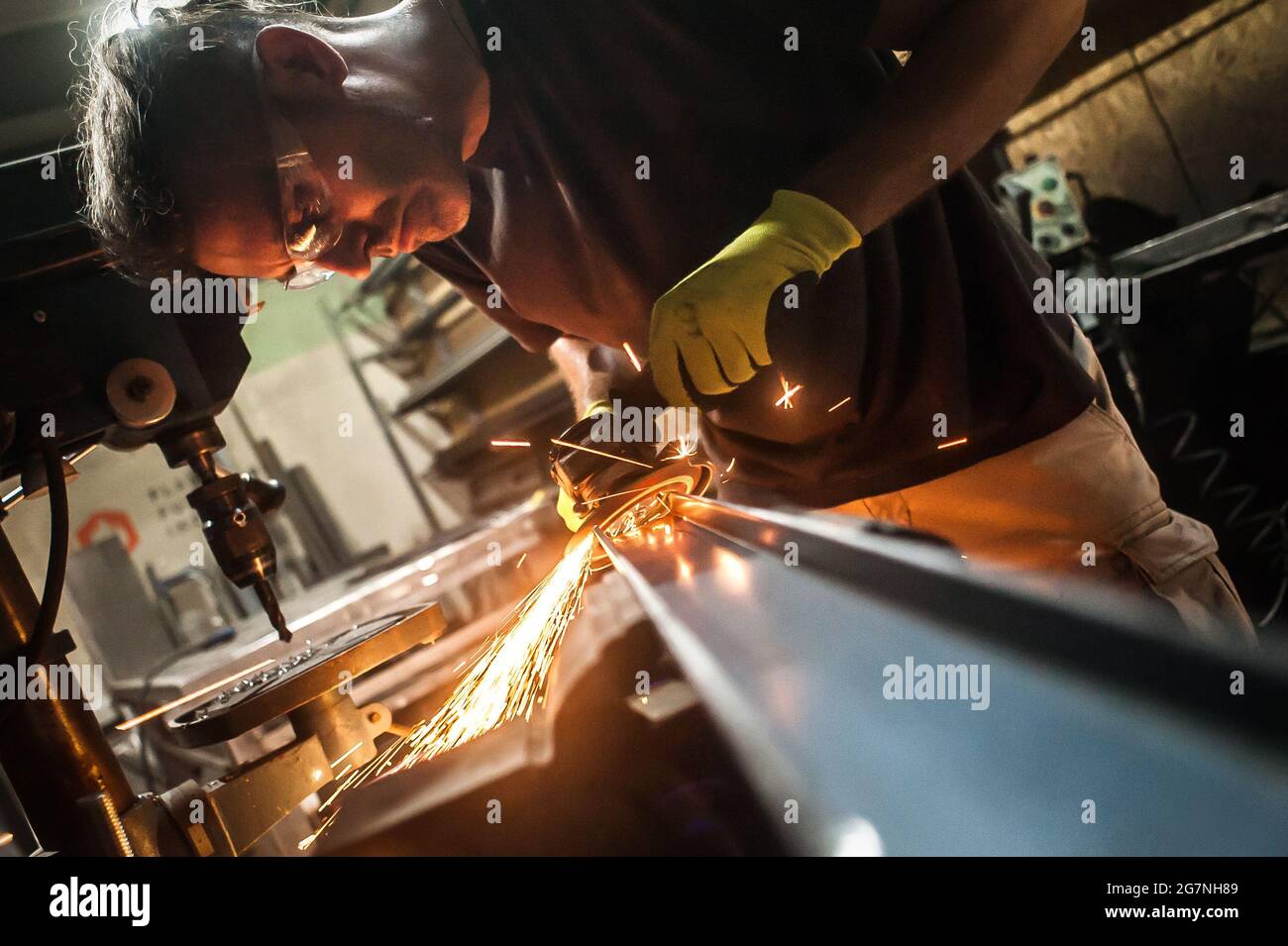 Man working with electric grinder tool on steel structure in factory ...