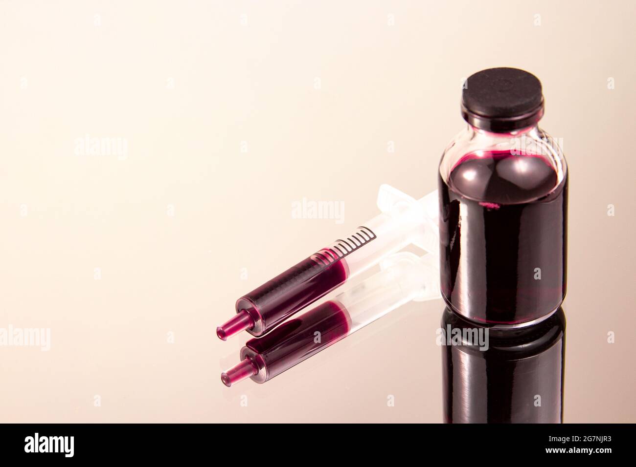 Disposable syringe and full container of red liquid. Blood test Stock ...