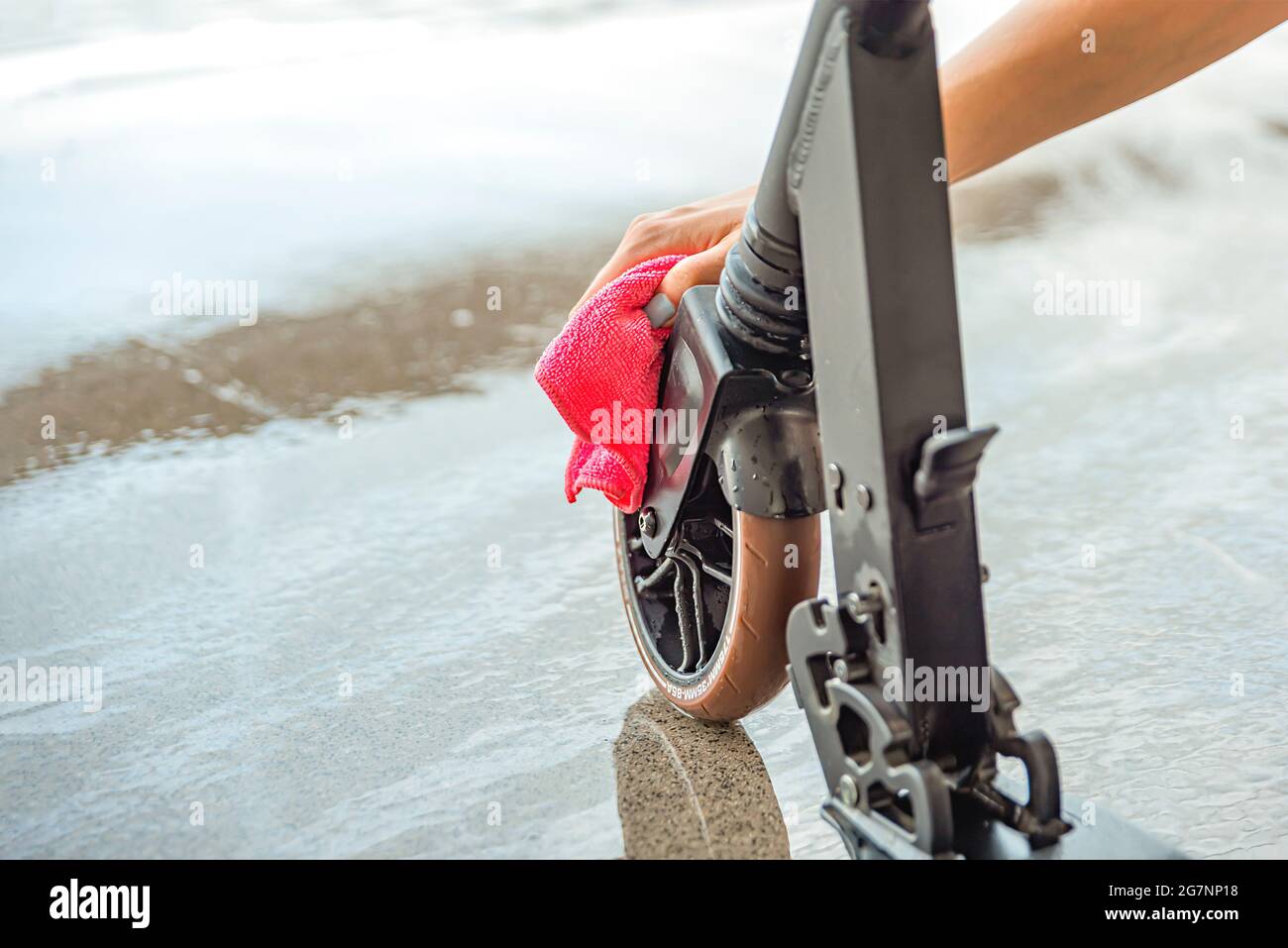 Cleaning or washing the scooter. Electric scooter care. A woman wipes a ...