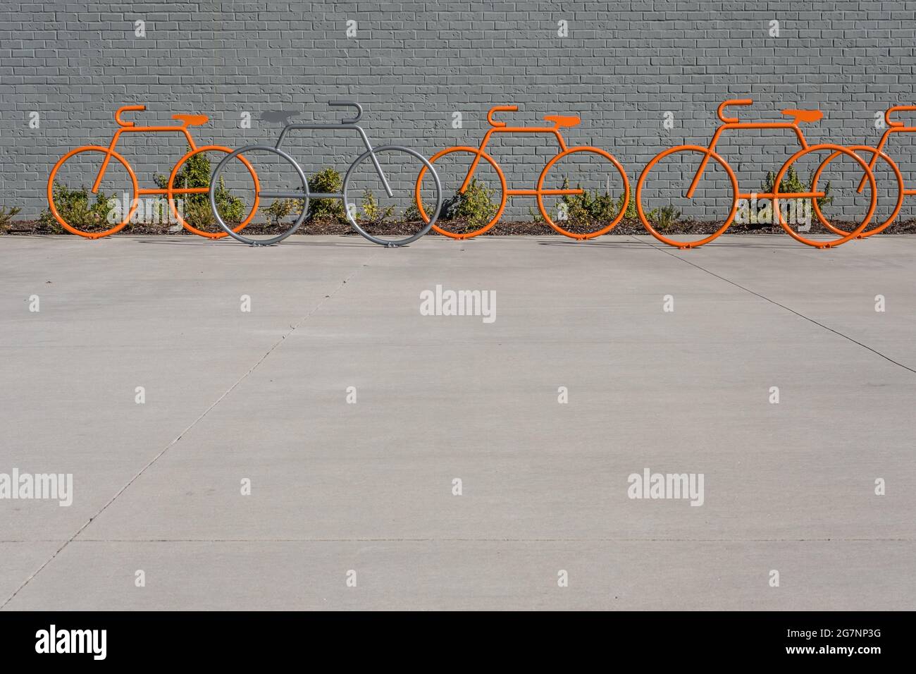 Tubular steel bicycles in a line attached to the cement alongside a ...