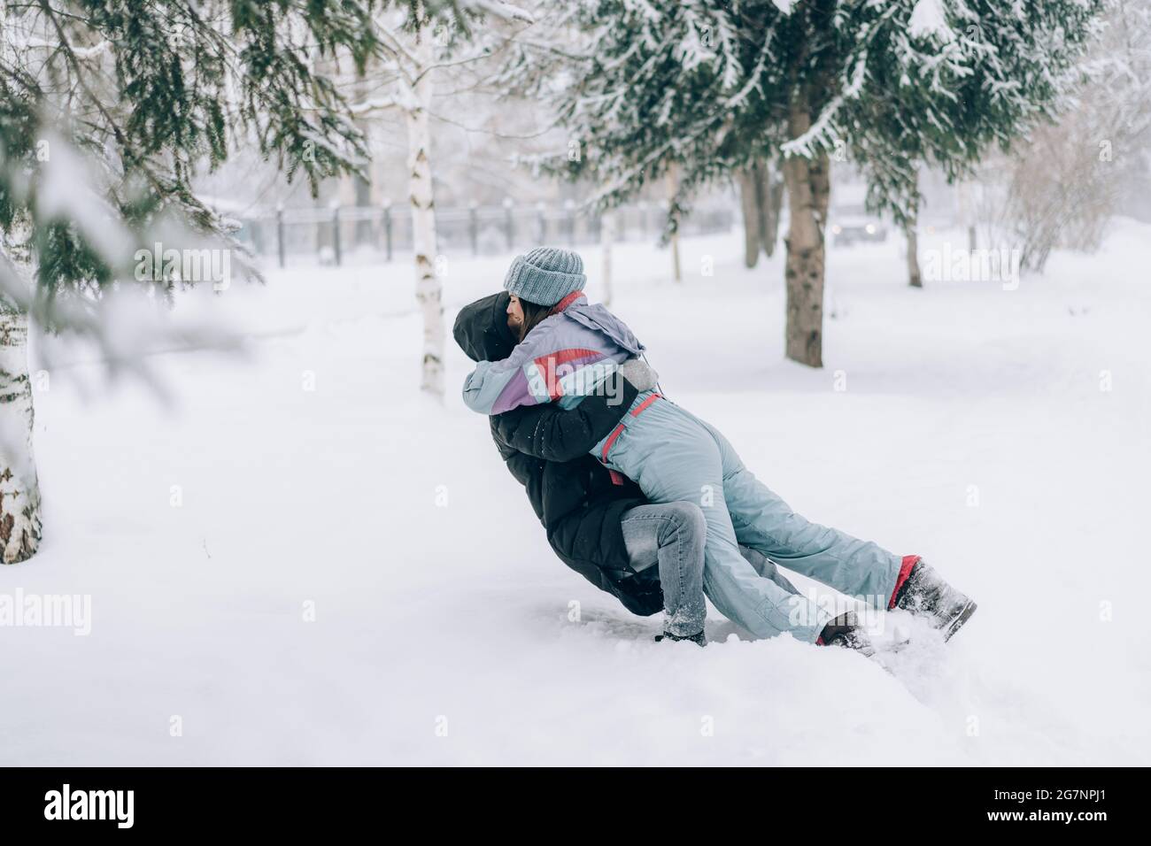 A guy and a girl are playing in the snow. Falling hugging people into ...