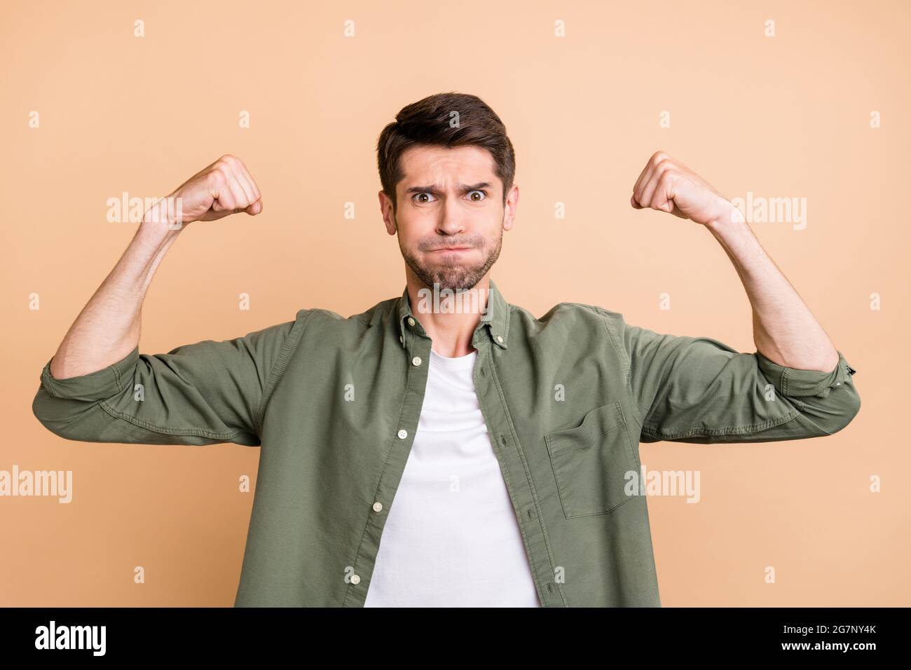 Photo of cute strong young gentleman wear khaki shirt showing arms ...