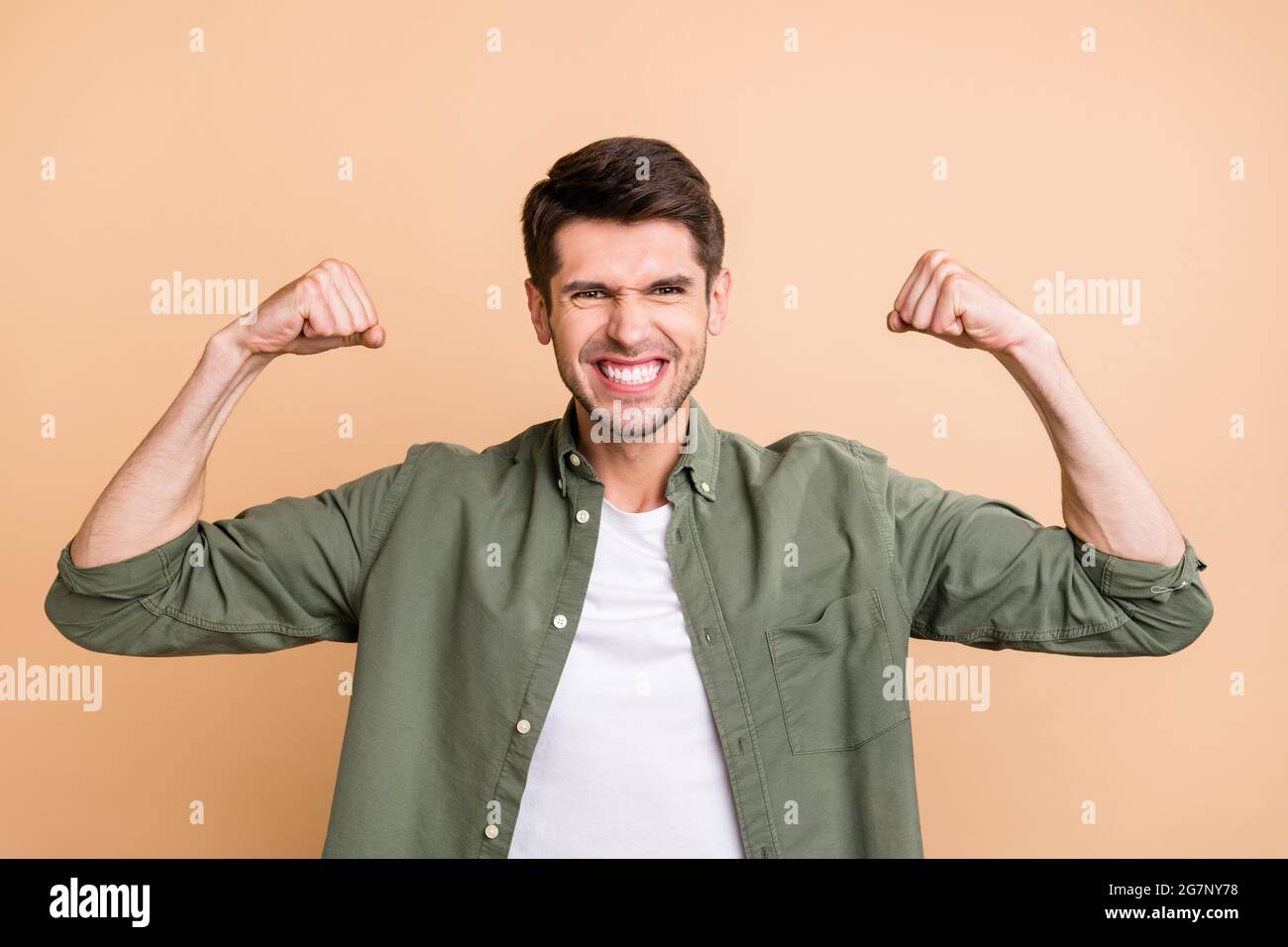 Photo of charming happy positive young man hold fists flex muscles ...
