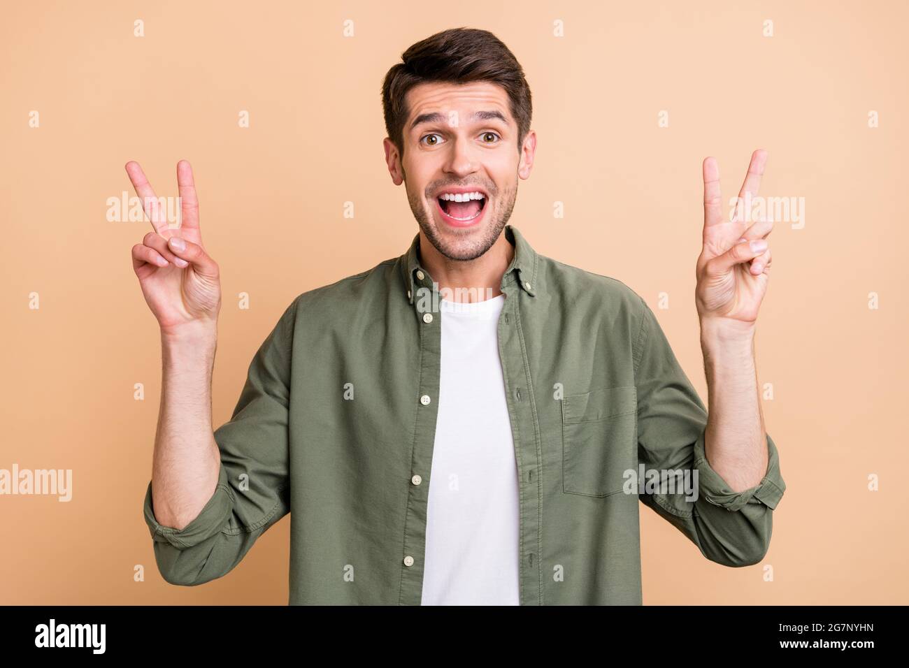 Photo of attractive happy amazed young man make v-signs good mood cool ...