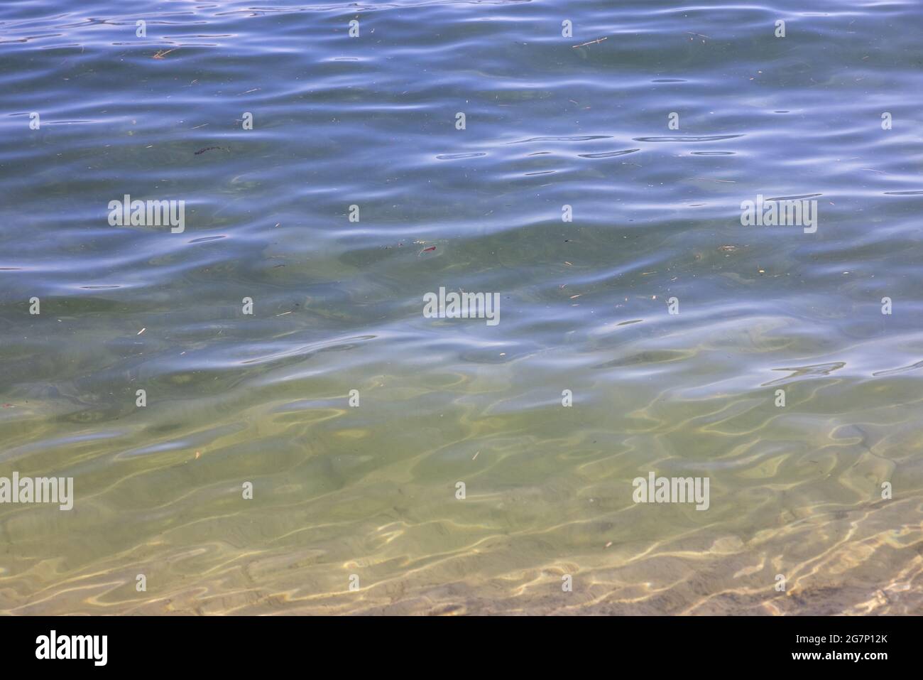 Closeup of a reflective clear body of water with waves crashing through ...