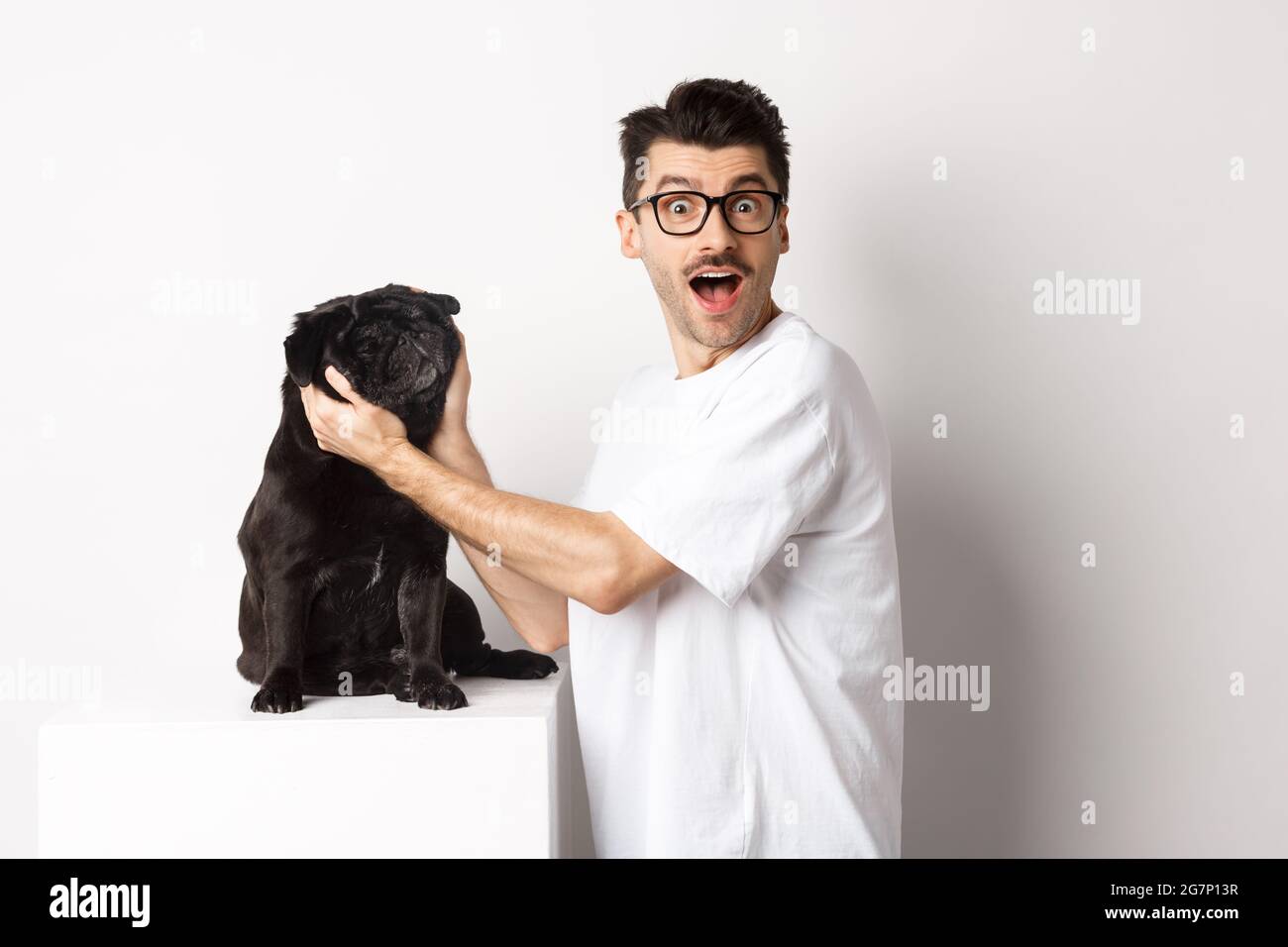 Happy young man showing you cute face of his pug. Dog owner loving his ...