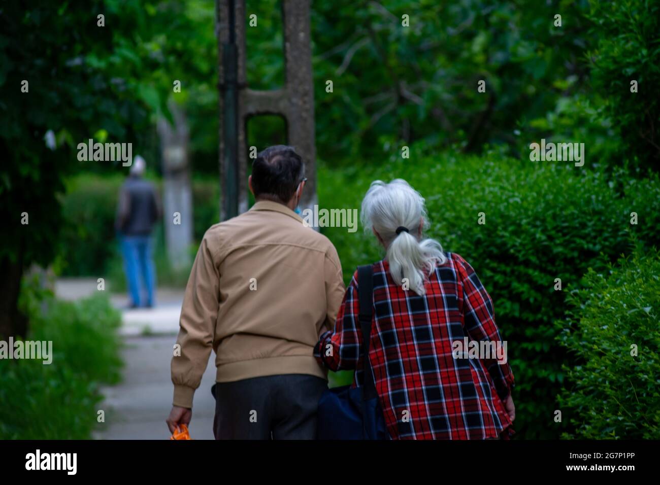Two elderly people walking on the street. Real people. View from behind ...