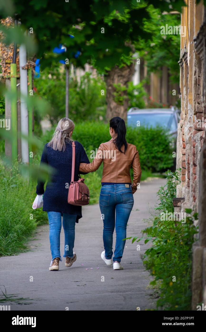 Two women walking on the street. Real people. View from behind Stock ...