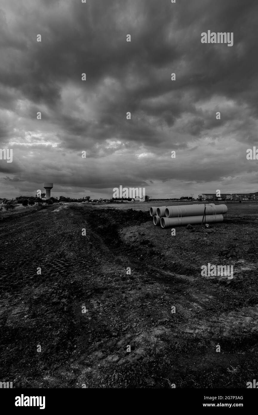 Stacked water main pipe with bell fitting next to an exposed trench for ...