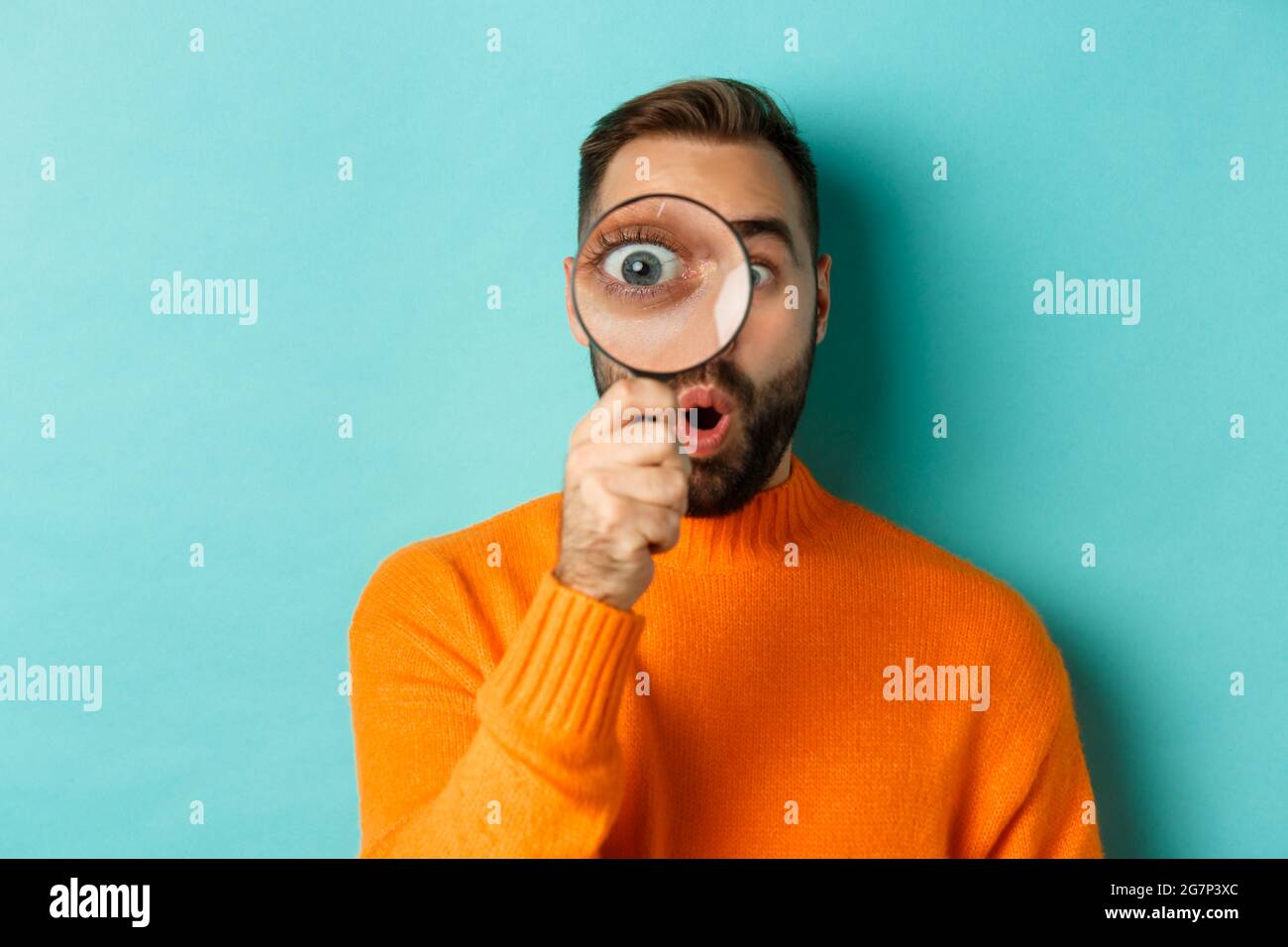 Funny man looking through magnifying glass, searching or investigating ...