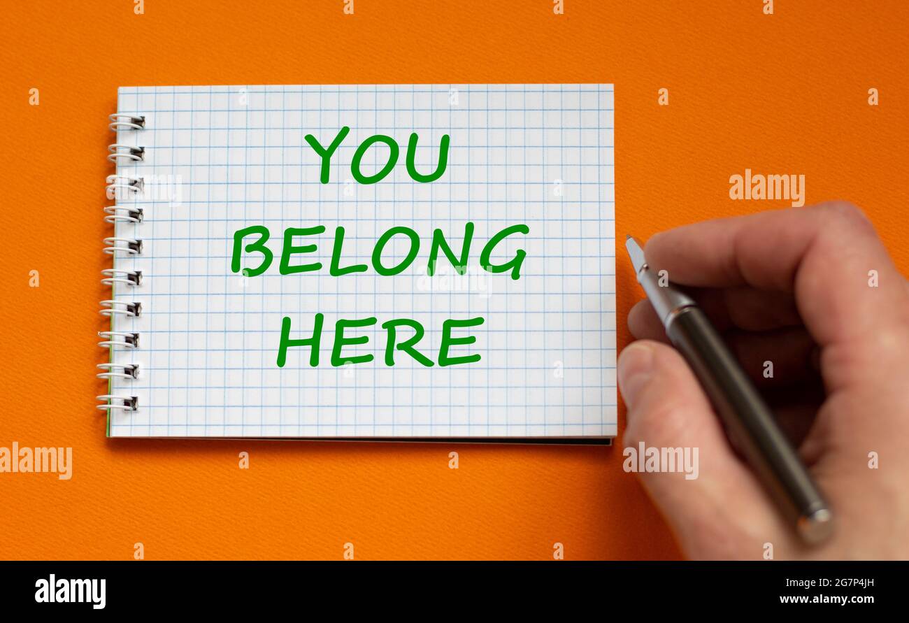 You belong here symbol. Businessman writing words You belong here on ...