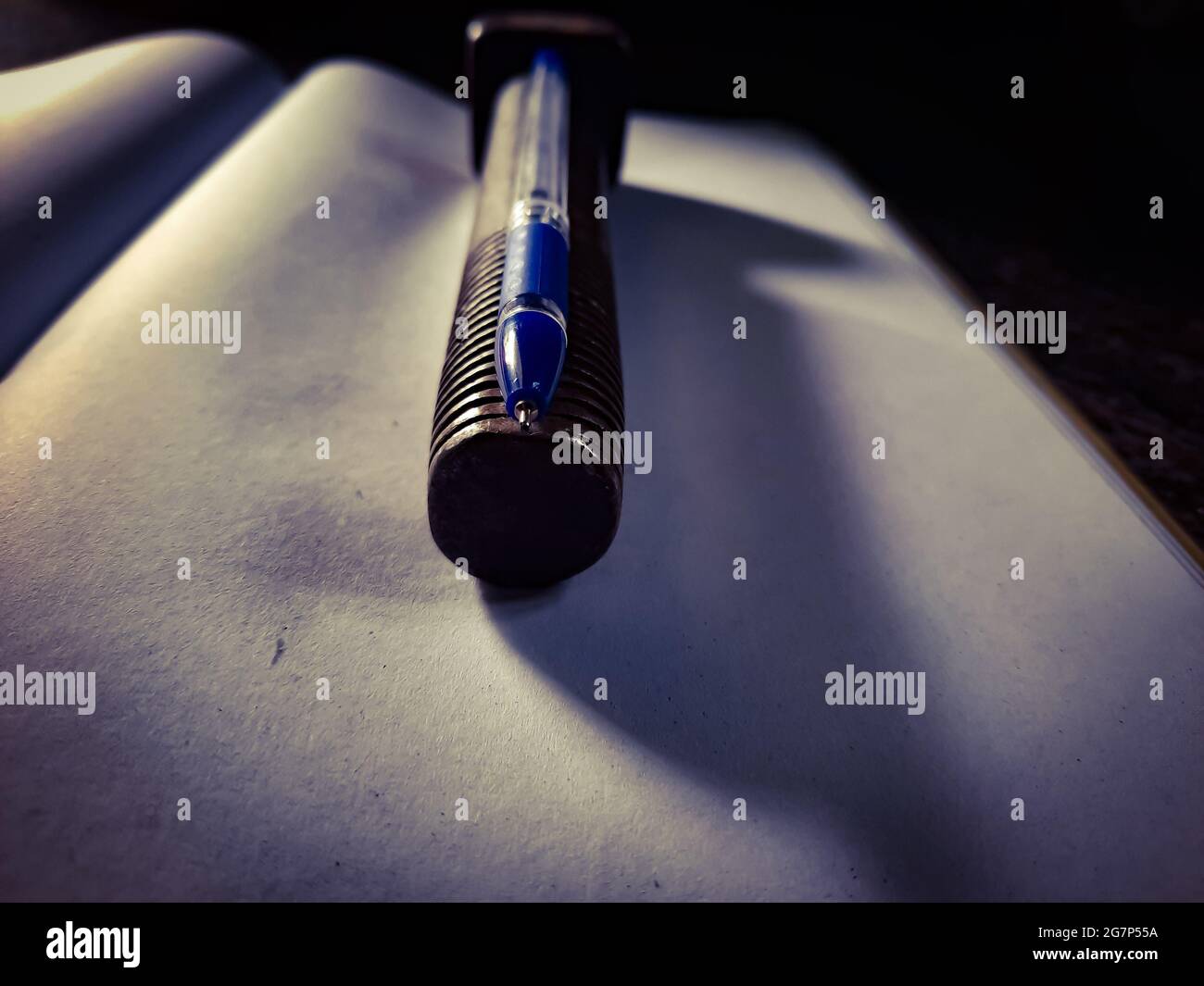 Closeup of a blue ball pen without a cap on the table with a dark ...