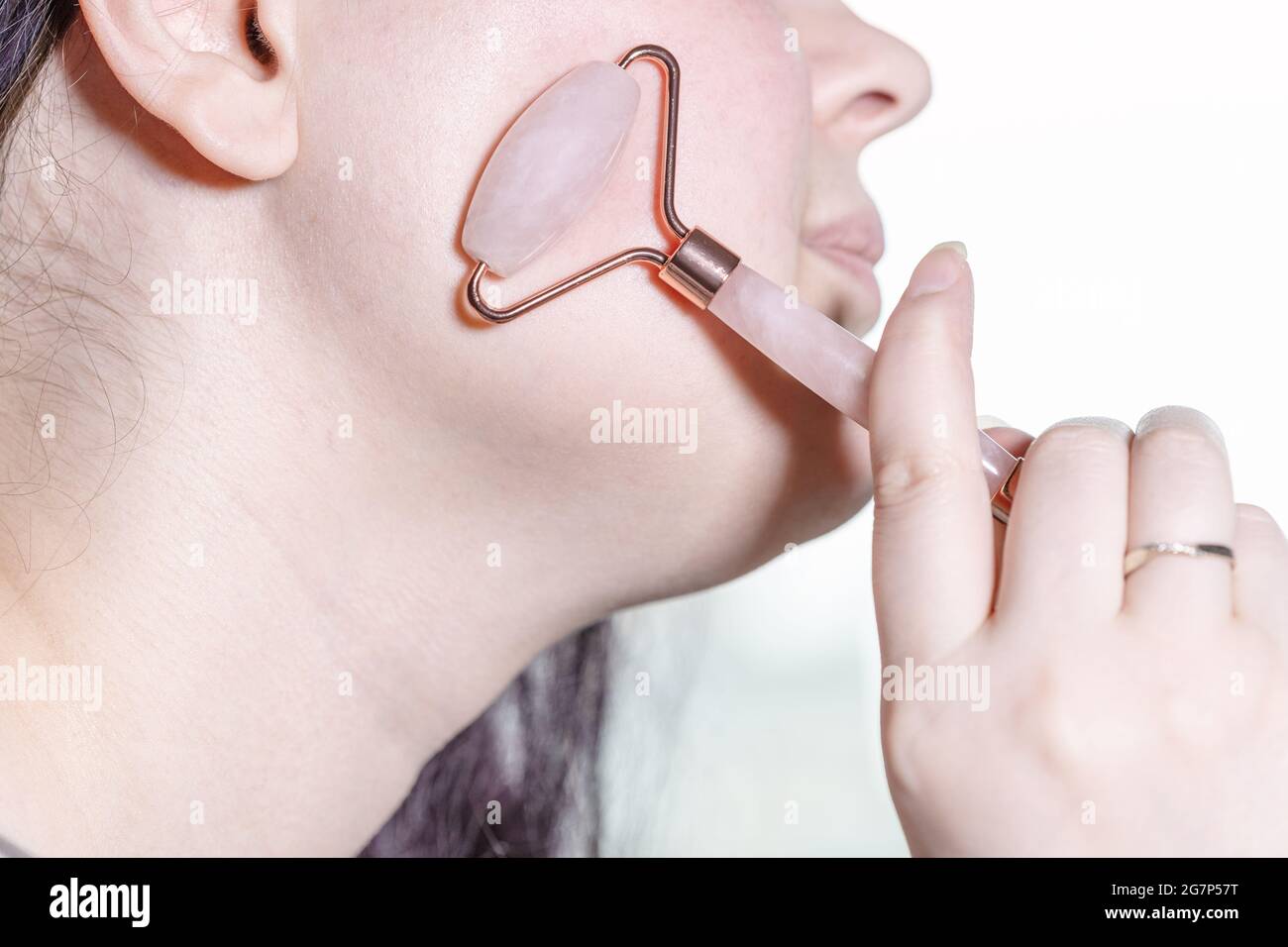 massaging cheek with quartz roller massager close up in technique of ...