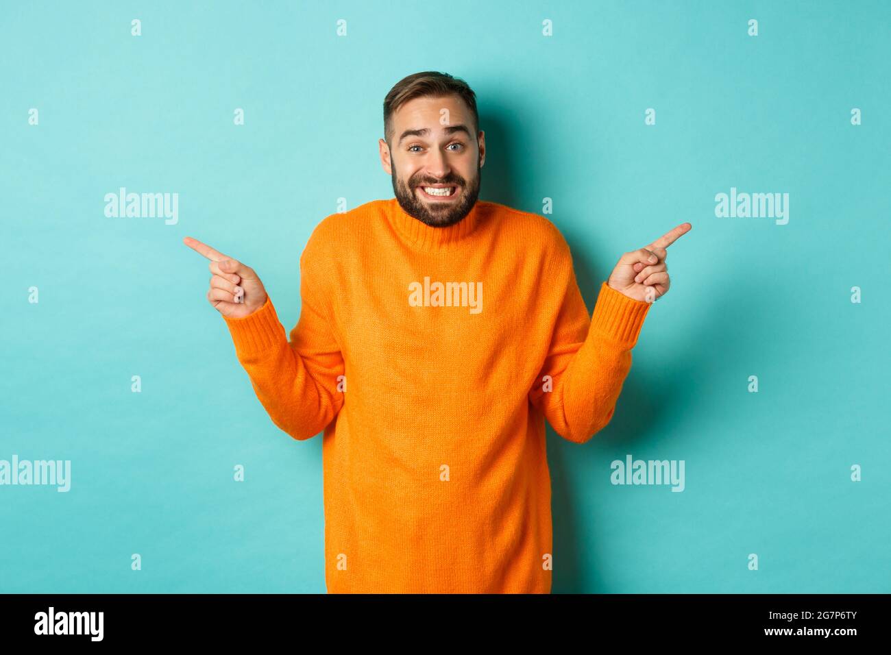 Confused handsome man shrugging indecisive, pointing fingers sideways ...