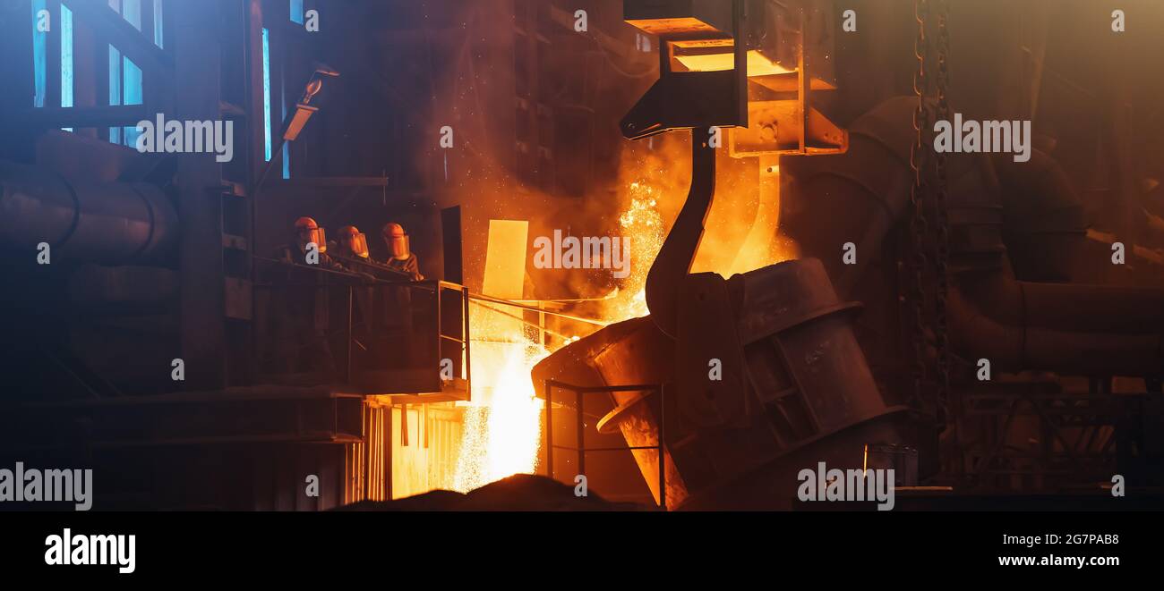 Metallurgical plant. Molten metal pouring from big ladle. Iron cast ...
