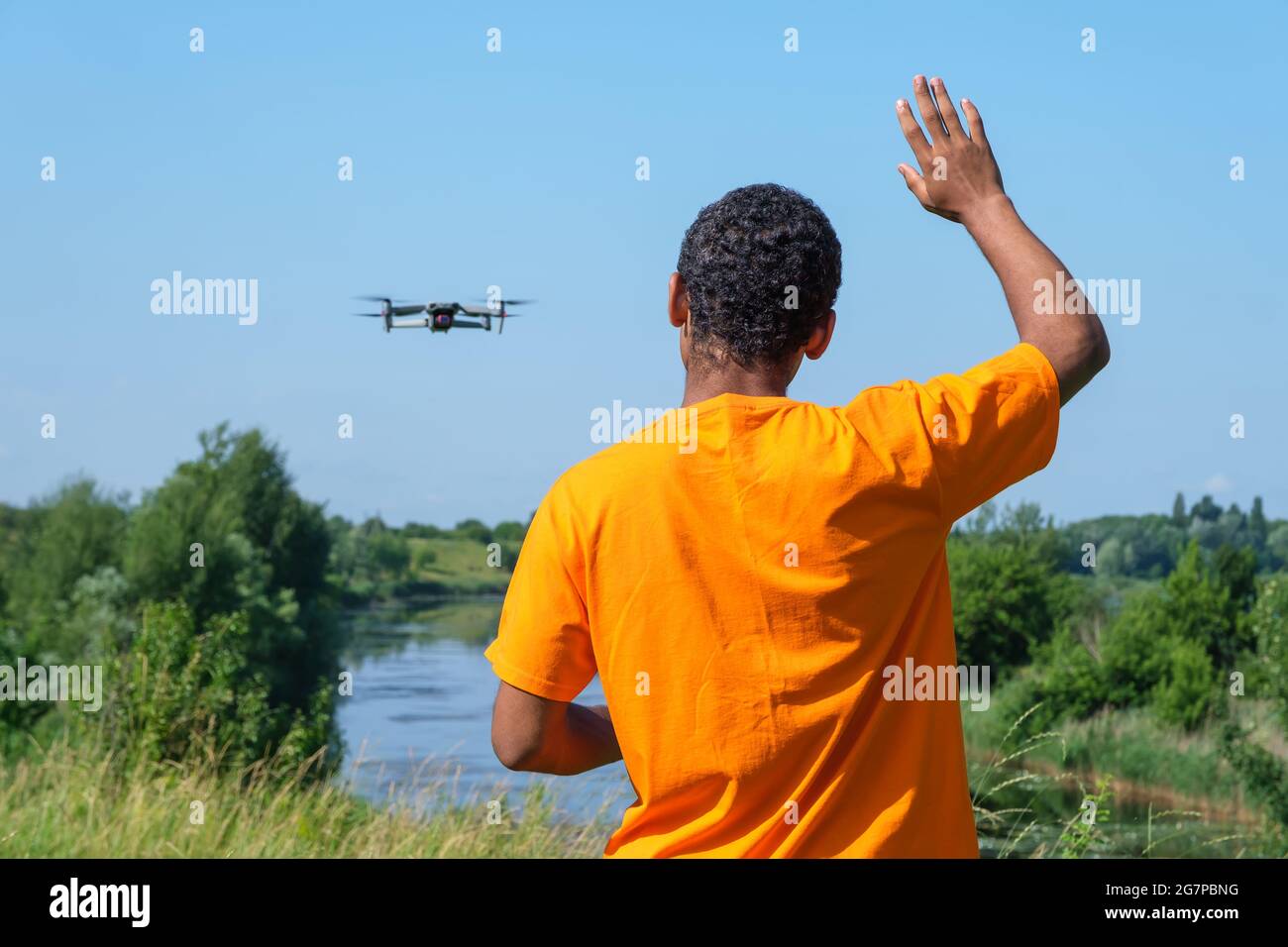African American man operating drone with controller on the meadow with ...
