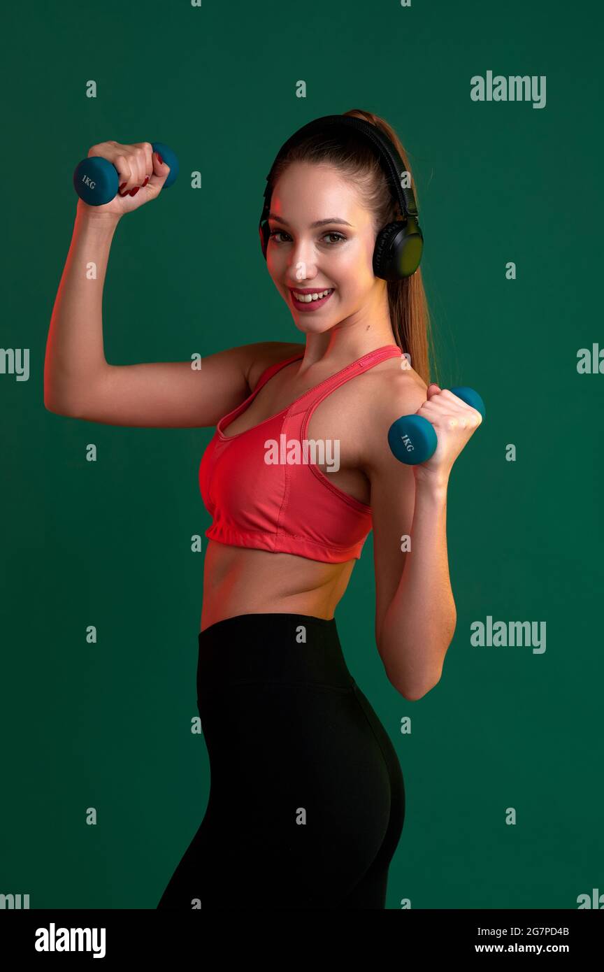 Fitness woman with strong body doing exercise with dumbbells indoors ...