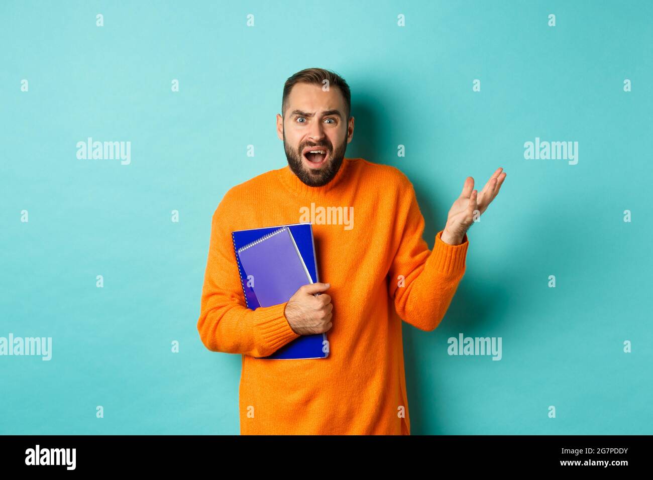 Education. Confused and disappointed man arguing, holding notebooks and ...