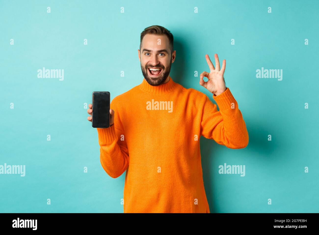 Photo of caucasian man showing mobile screen and okay sign, approve ...