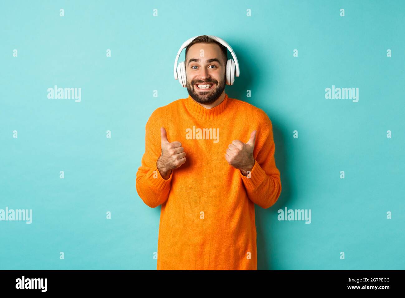Amazed adult man listening music in headphones, looking at camera ...
