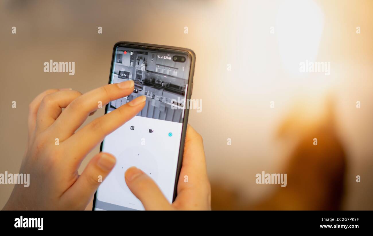 Female hand holding and zoom smartphone for watching home security ...
