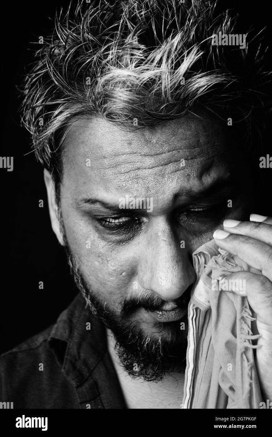Grayscale portrait of a man with partially closed eyes holding a piece ...