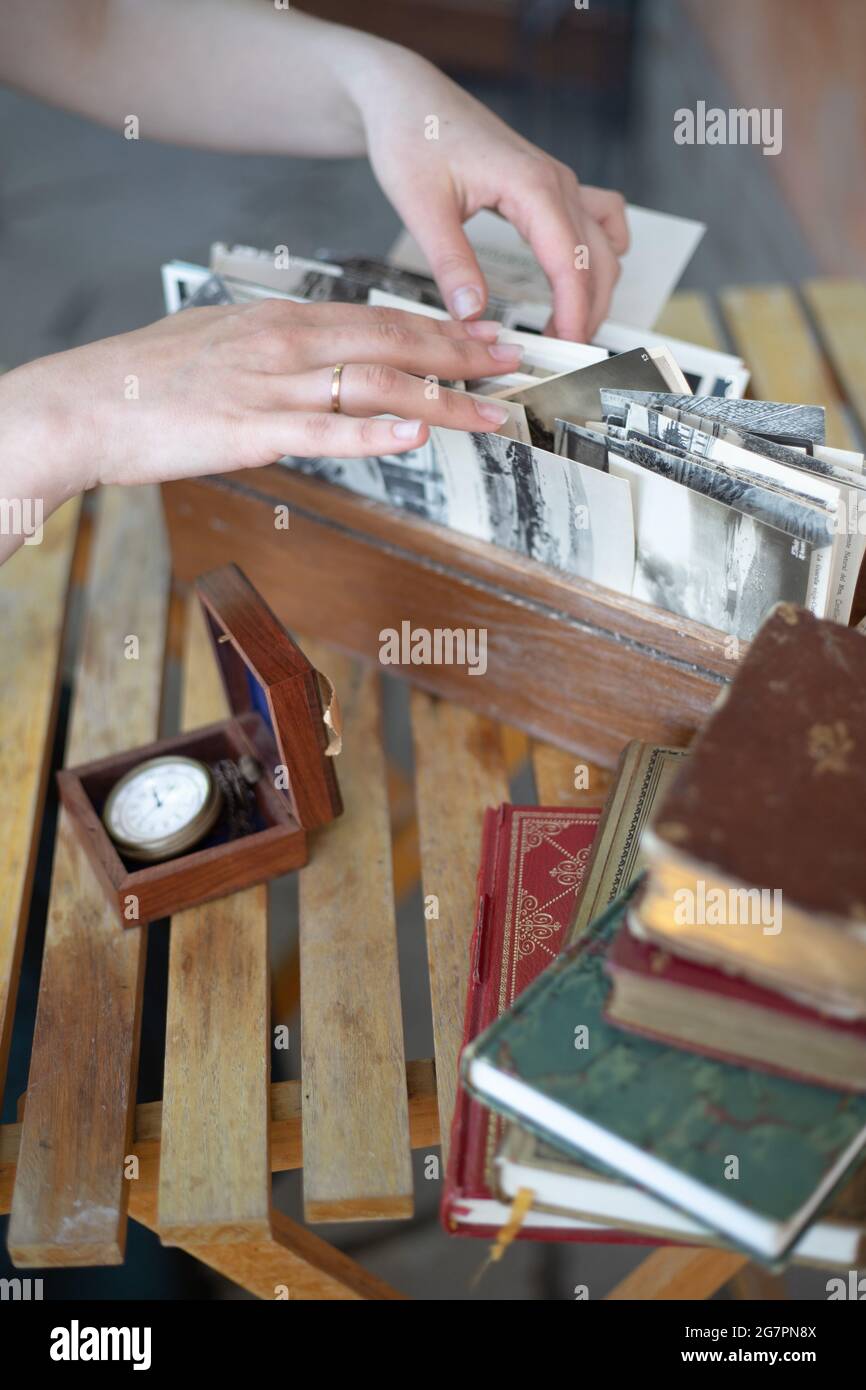 Vertical shot of a person looking at old pictures with vintage objects ...