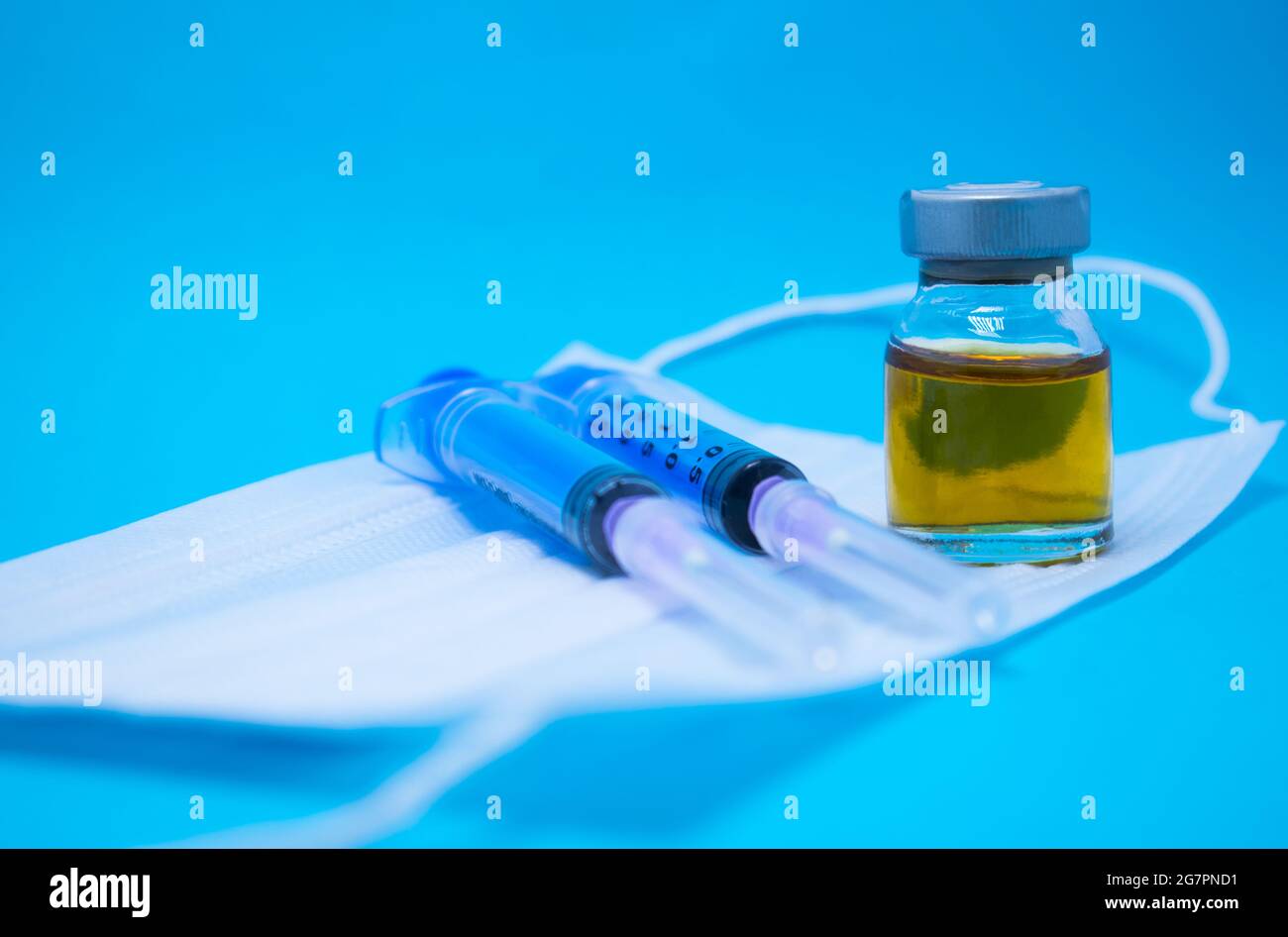 Closeup shot of a vail and syringes on a face mask isolated on a light ...