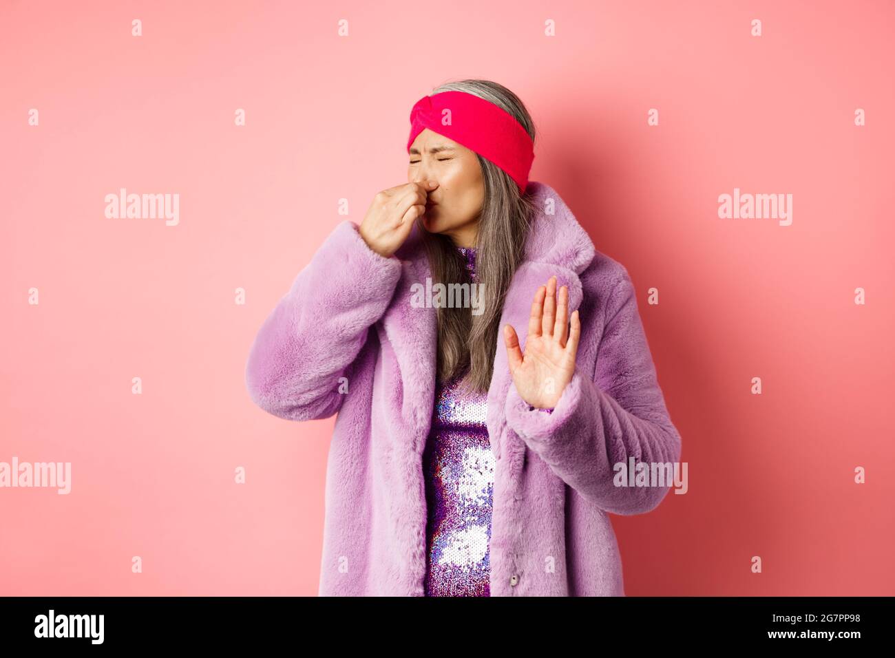 Disgusted asian mature woman in trendy purple winter coat and dress ...