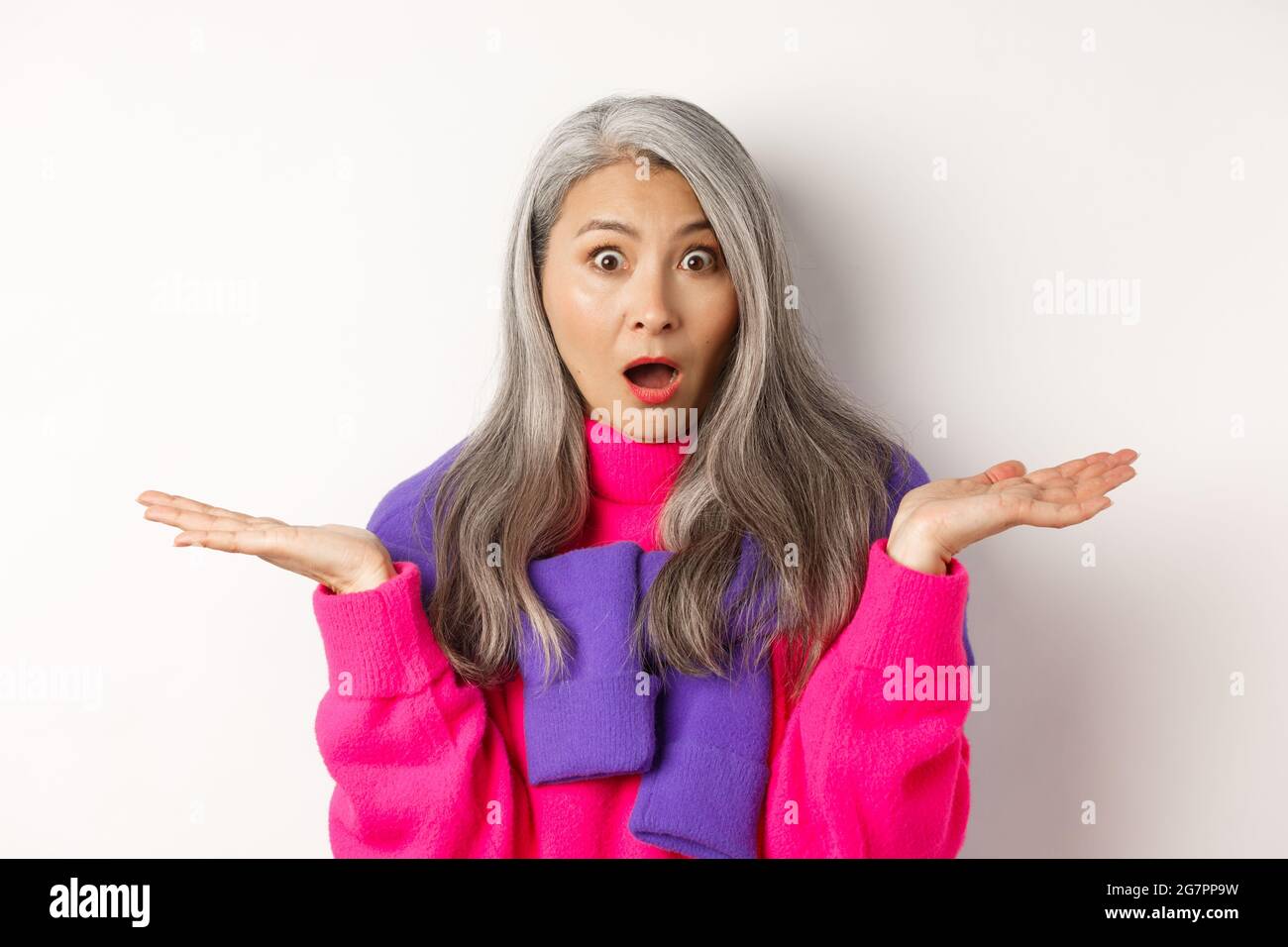 Close up of shocked asian mom staring at camera, spread hands sideways ...