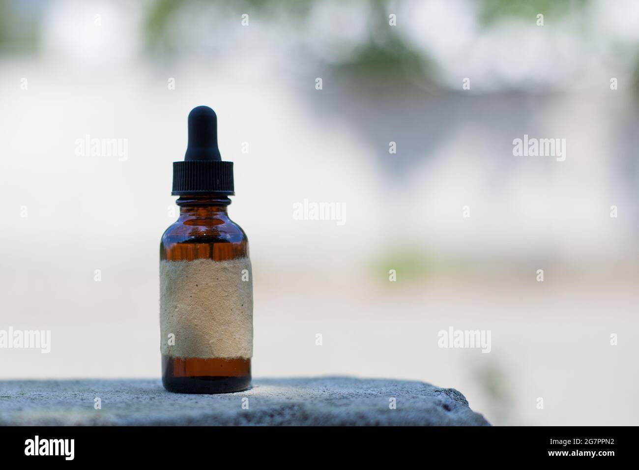 Closeup shot of a brown glass dropper bottle of natural oil put outside ...