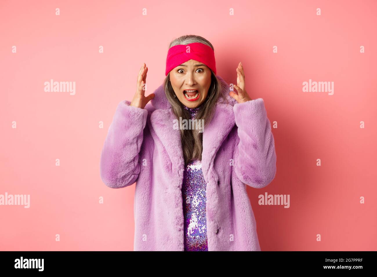 Anxious asian senior woman in stylish faux fur coat screaming, shaking ...