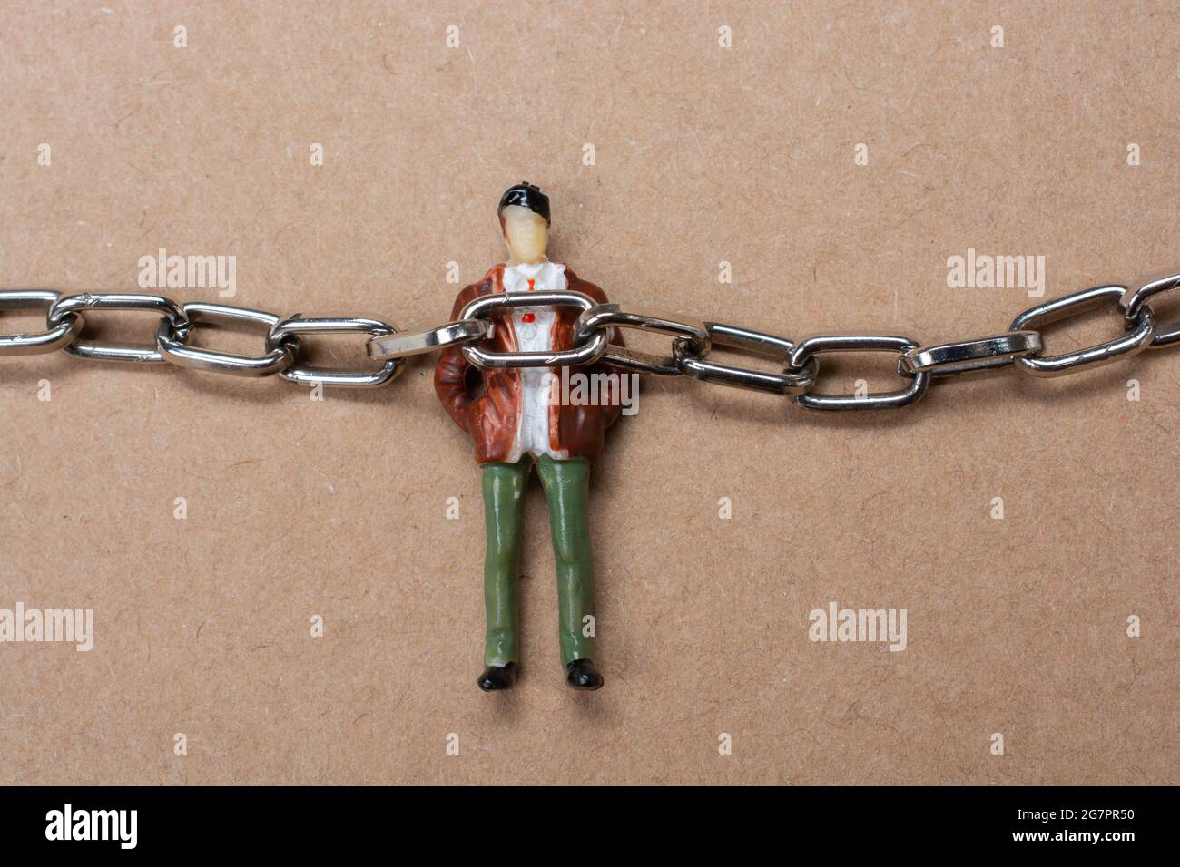 Closeup of a tiny man figurine and a metal chain Stock Photo - Alamy
