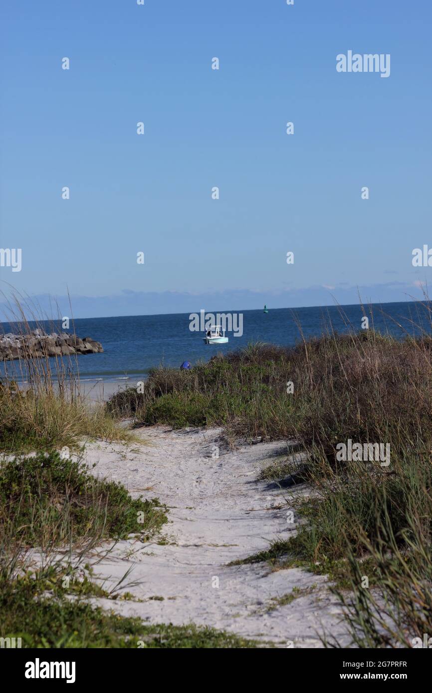 Walking on the path between the sand dunes to the beach toe see a boat ...