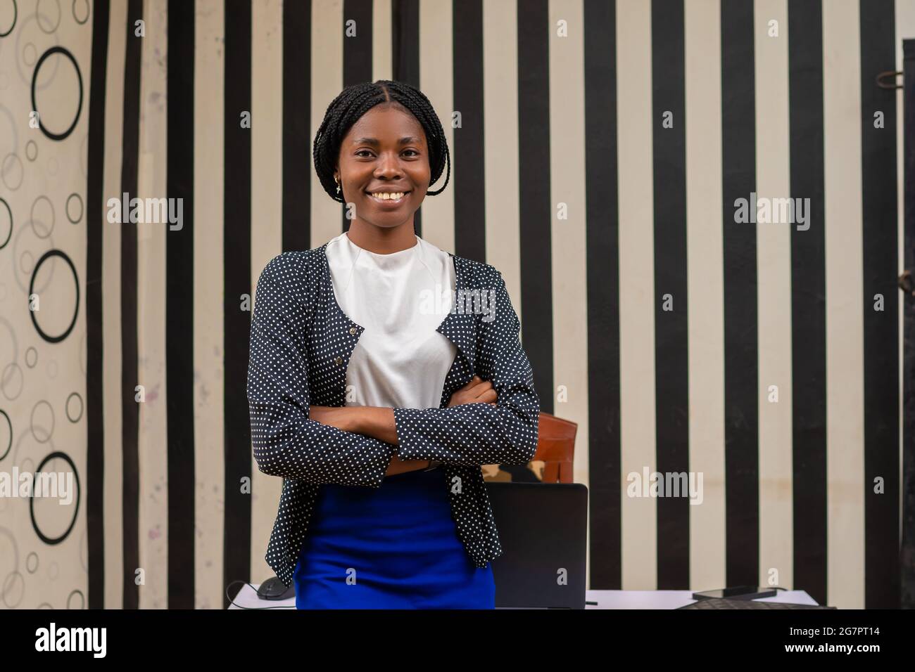 Happy Nigerian woman with crossed arms and a smile in the office after ...