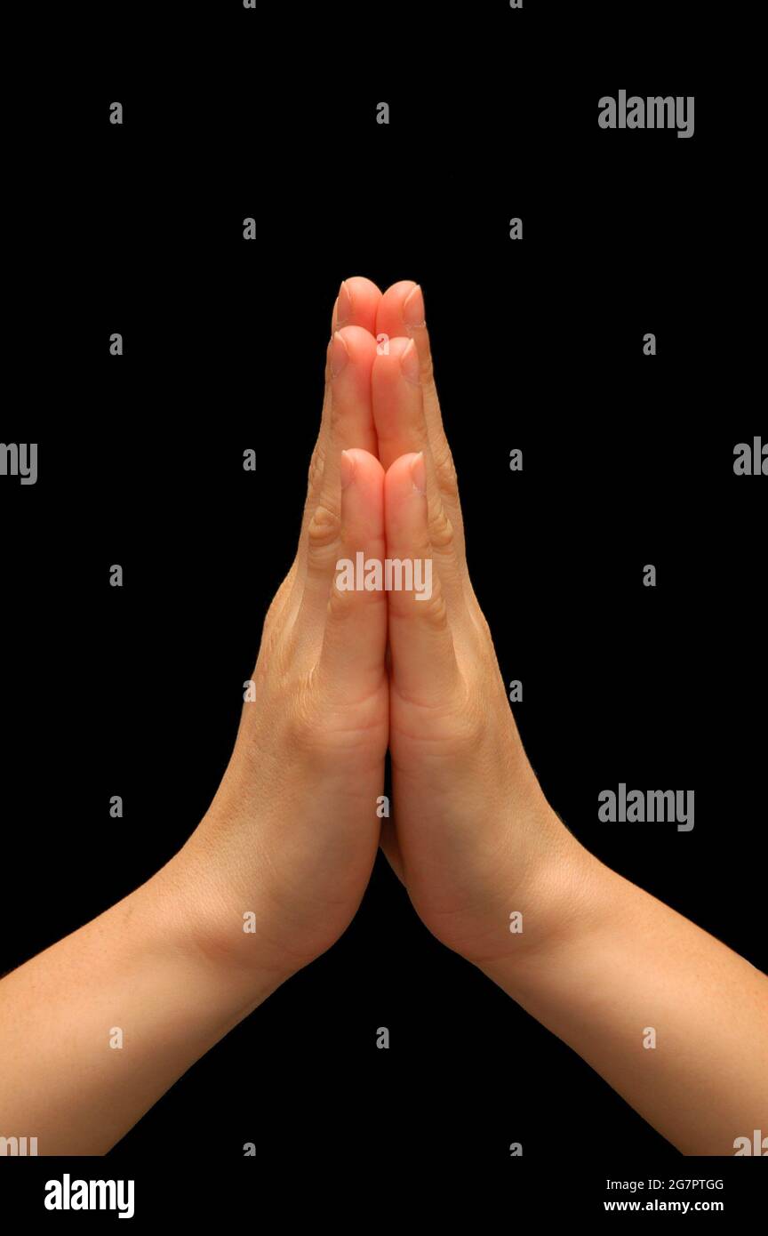 Closeup of a praying hand gesture isolated on a black background with ...