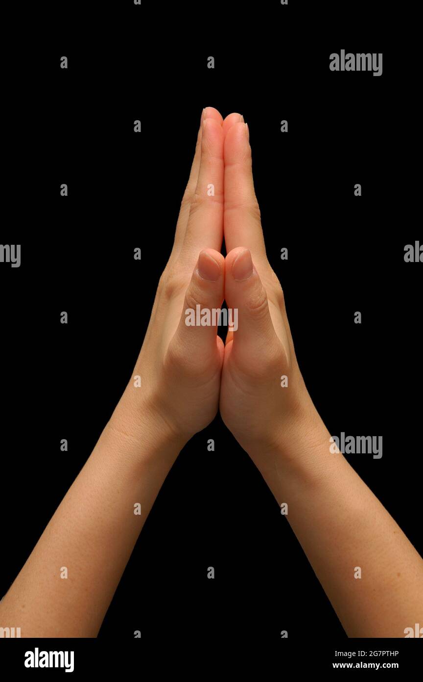 Closeup of a praying hand gesture isolated on a black background with ...
