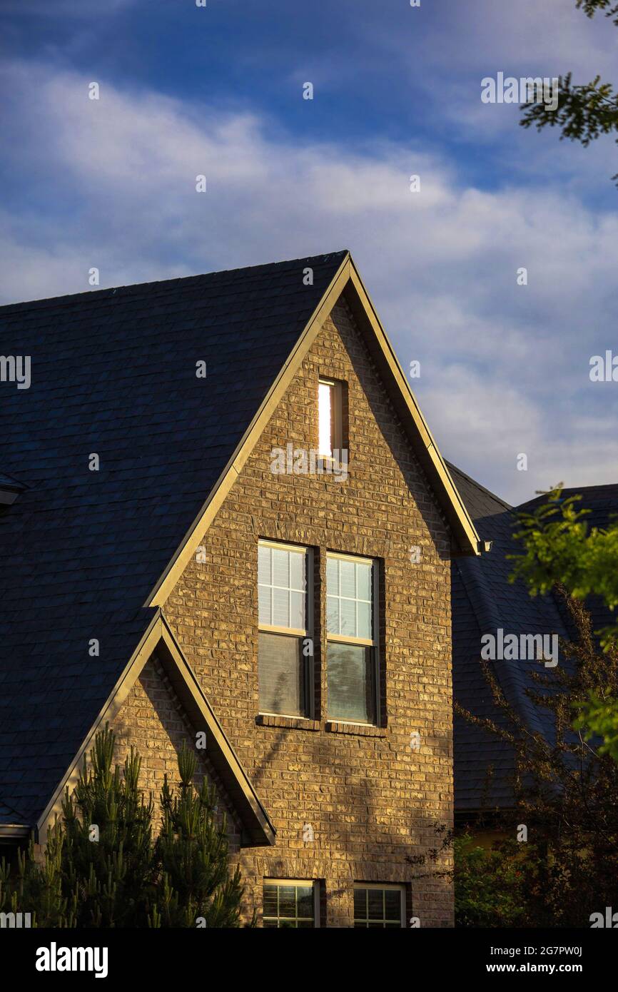 Rooftop of a brick house with attic and windows and under the blue sky ...
