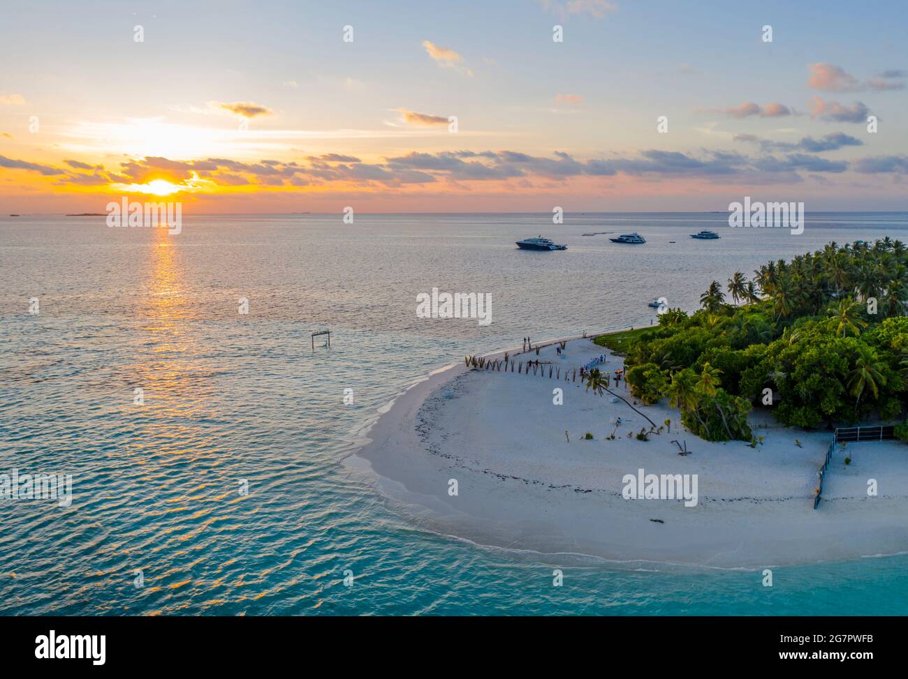 Aerial view of the sunset over a sandy island with palm trees and ...