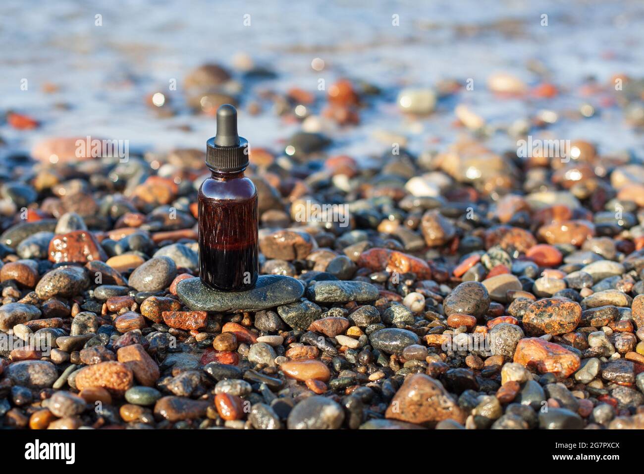 Closeup shot of a bottle with black liquid on the rock surface ...