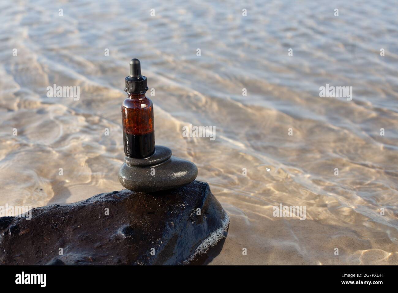 Closeup shot of a bottle with black liquid on the rock surface ...