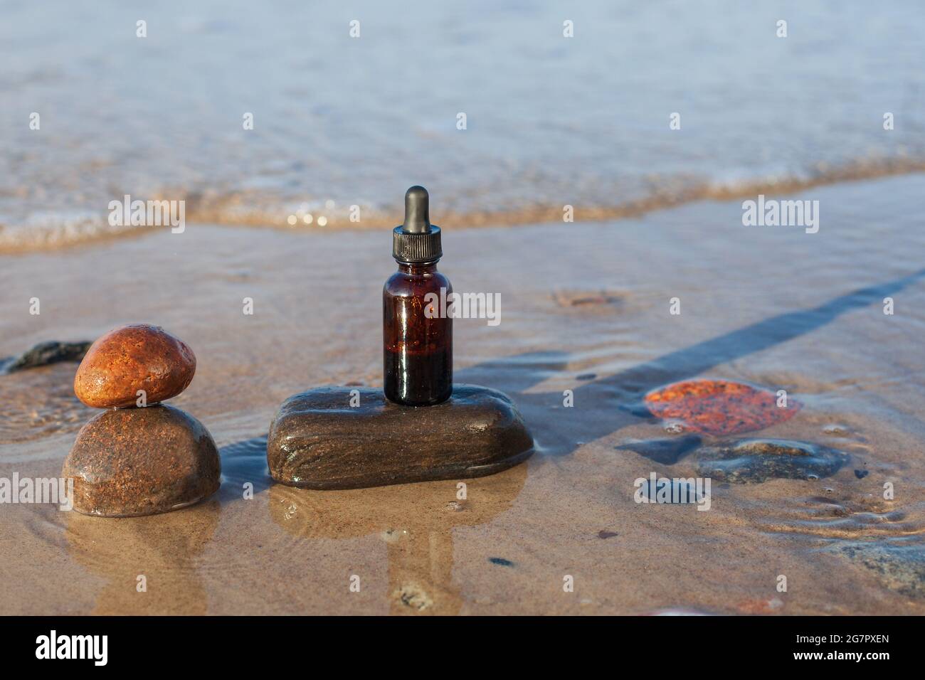 Closeup shot of a bottle with black liquid on the rock surface ...