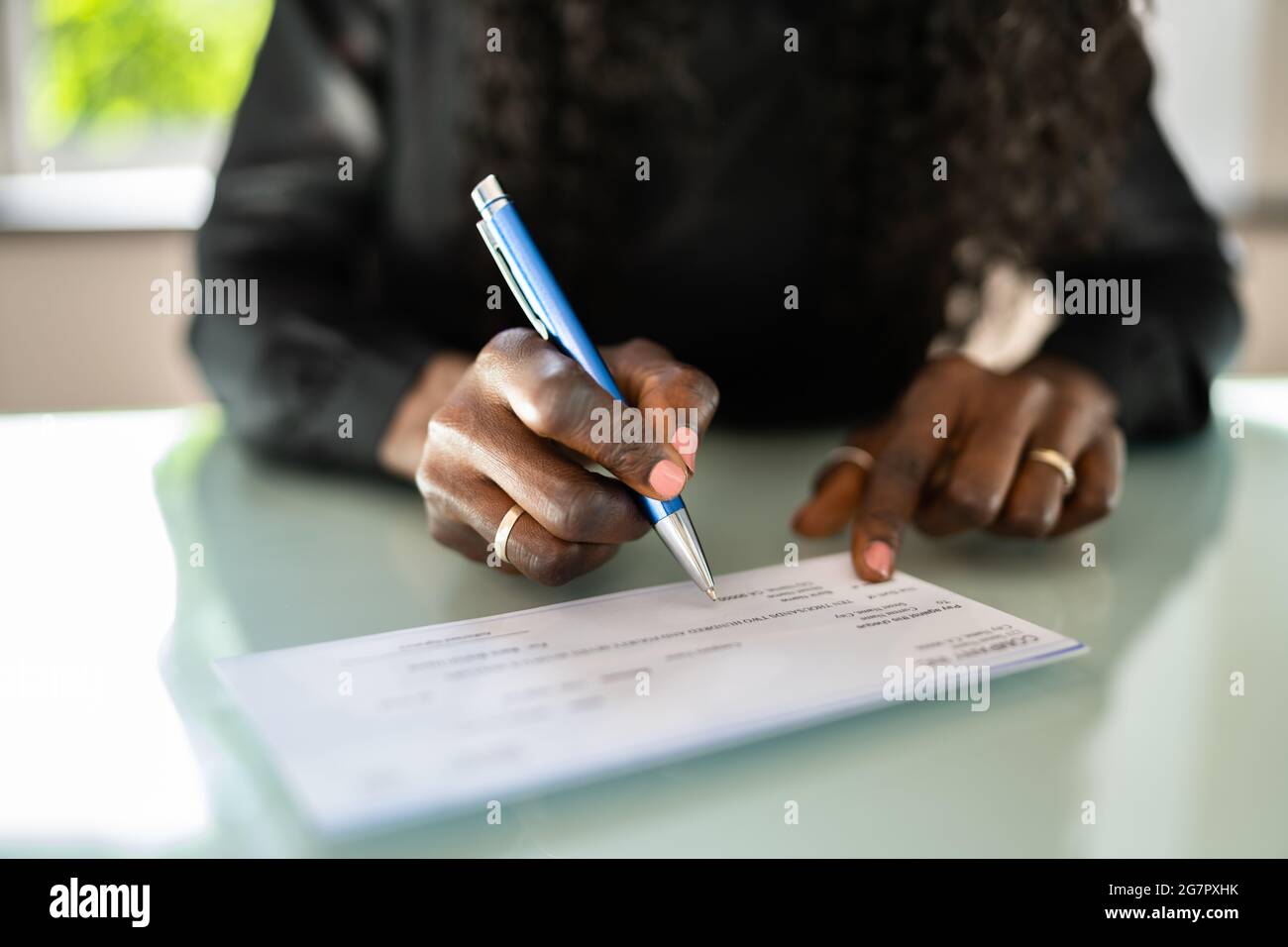 African Woman Writing Check. Payroll Salary Cheque Stock Photo - Alamy