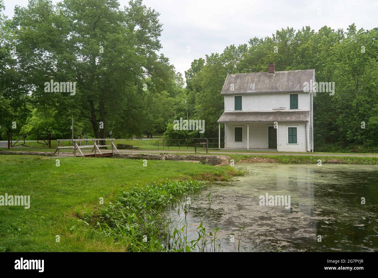 Small white house with green windows standing behind a small river ...