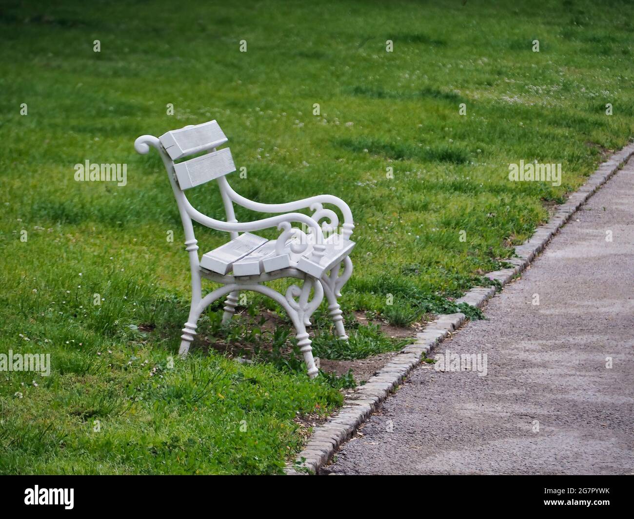 White bench on a grassy area by the asphalt pathway Stock Photo - Alamy