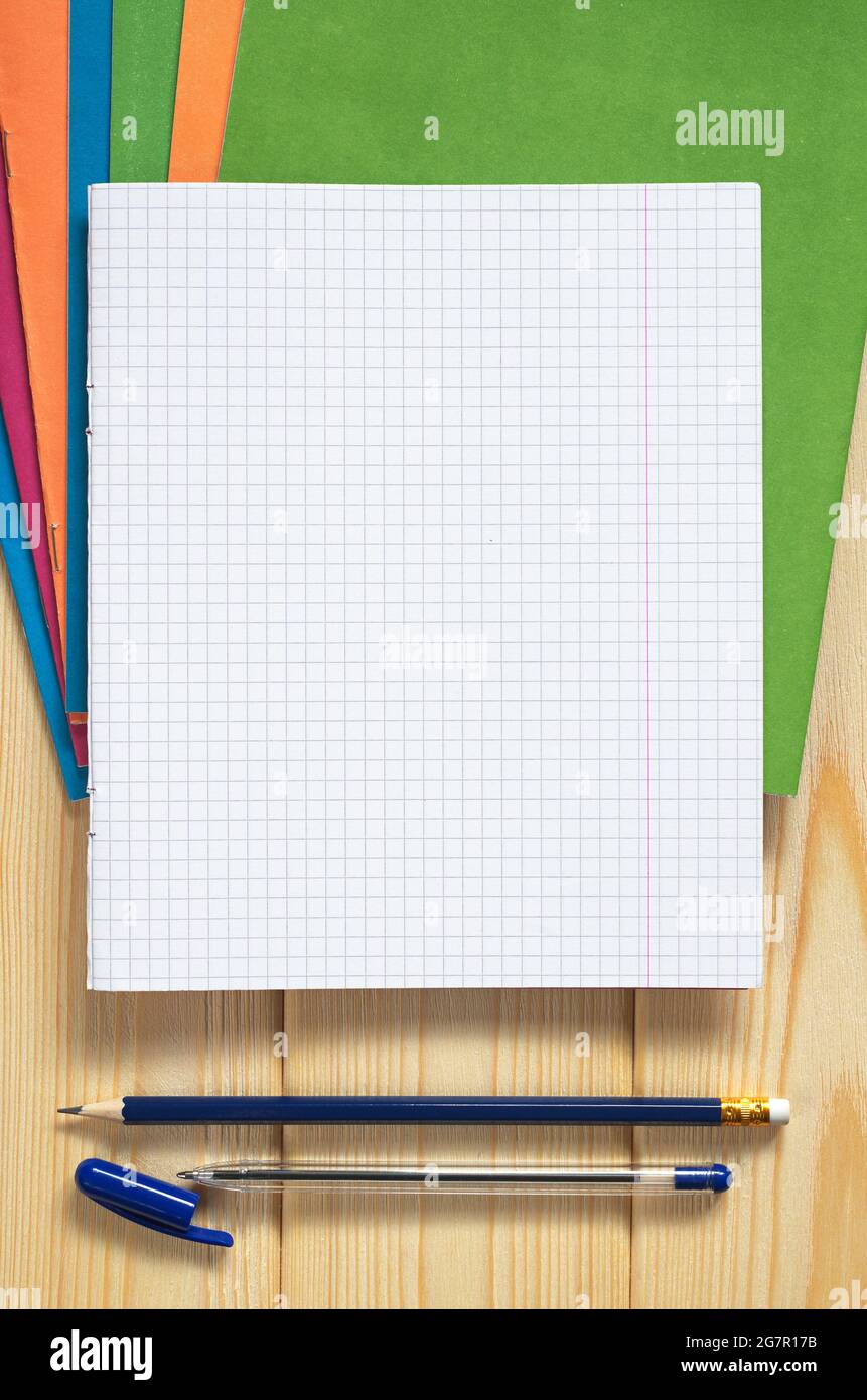 Open school notebook, pencil and pen on wooden table, top view. Space ...